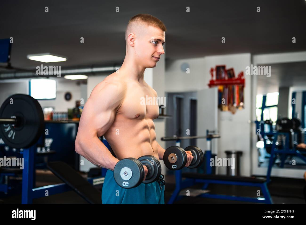 A young man lifting weights in a gym. Professional bodybuilder training ...
