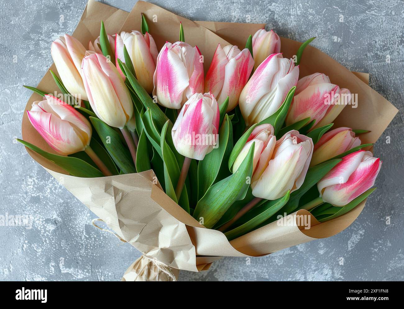 bouquet of pink and white tulips wrapped in brown paper. The tulips are ...