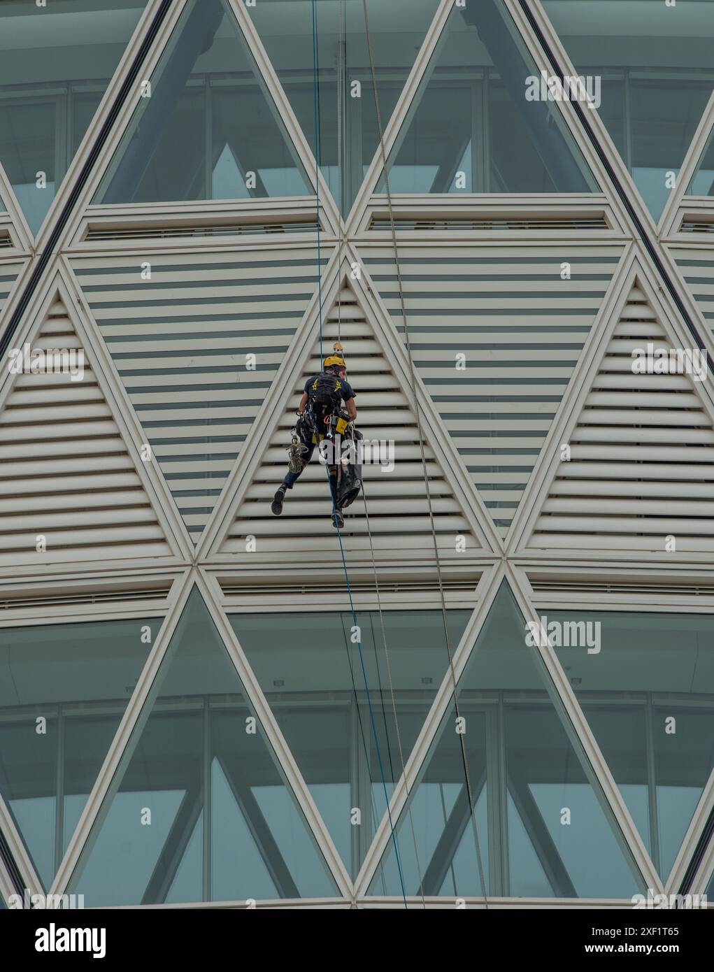 Milan Italy 29 June 2024: A rope operator with a harness, lowering ...