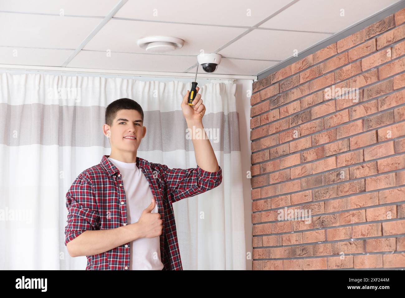 Technician showing thumbs up while installing CCTV camera with ...