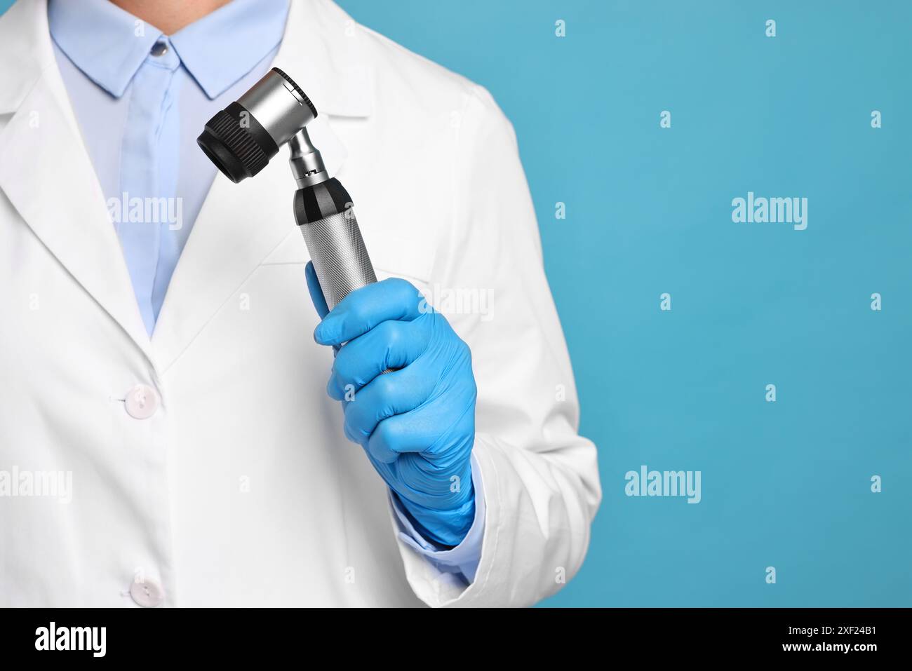 Dermatologist with dermatoscope on light blue background, closeup ...