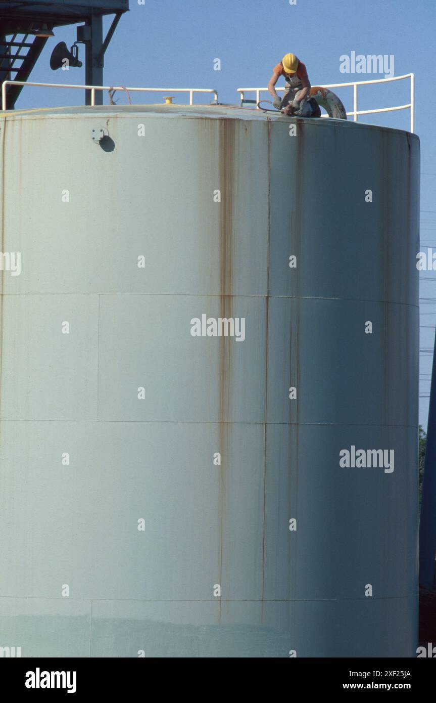 Workman on top of storage tank cleaning Stock Photo - Alamy