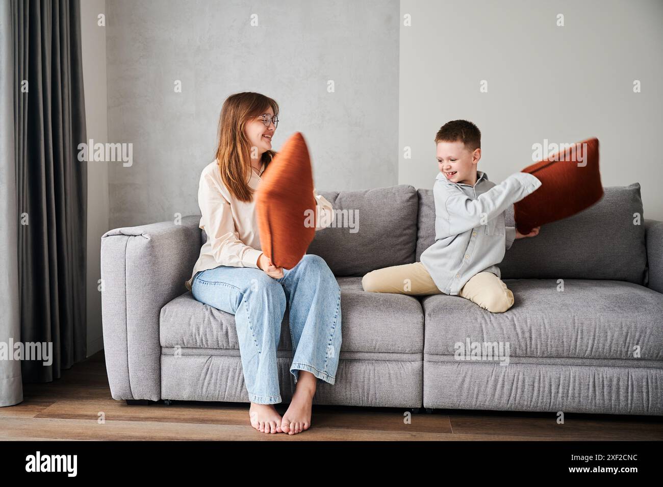 Two young siblings started a pillow fight on couch. Little boy and her ...