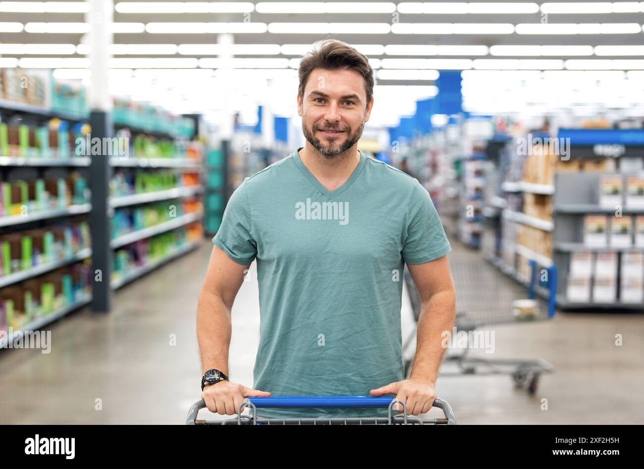 Portrait of man with shopping cart in a store. Supermarket shopping and ...