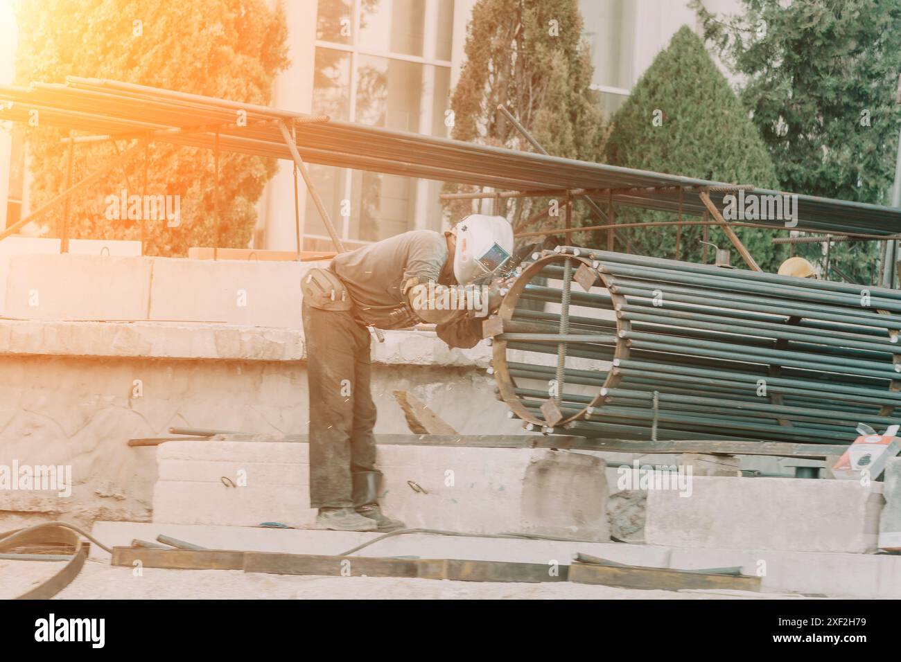 A man in a welding mask welds reinforcement for concrete construction ...