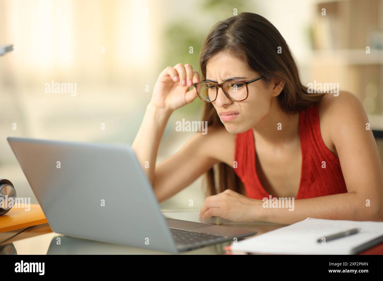 Student forcing sight wearing glasses checking laptop at home Stock ...