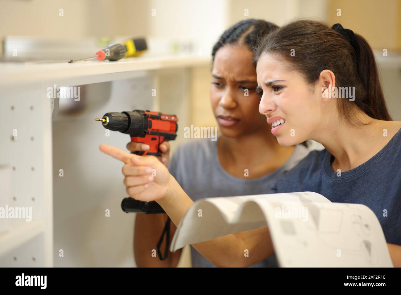 Confused roommates installing furniture holding instructions manual in ...