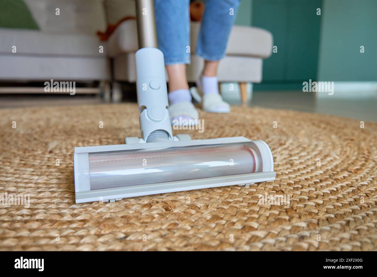 Close up of vacuum cleaner brush cleaning carpet on floor. Woman using ...