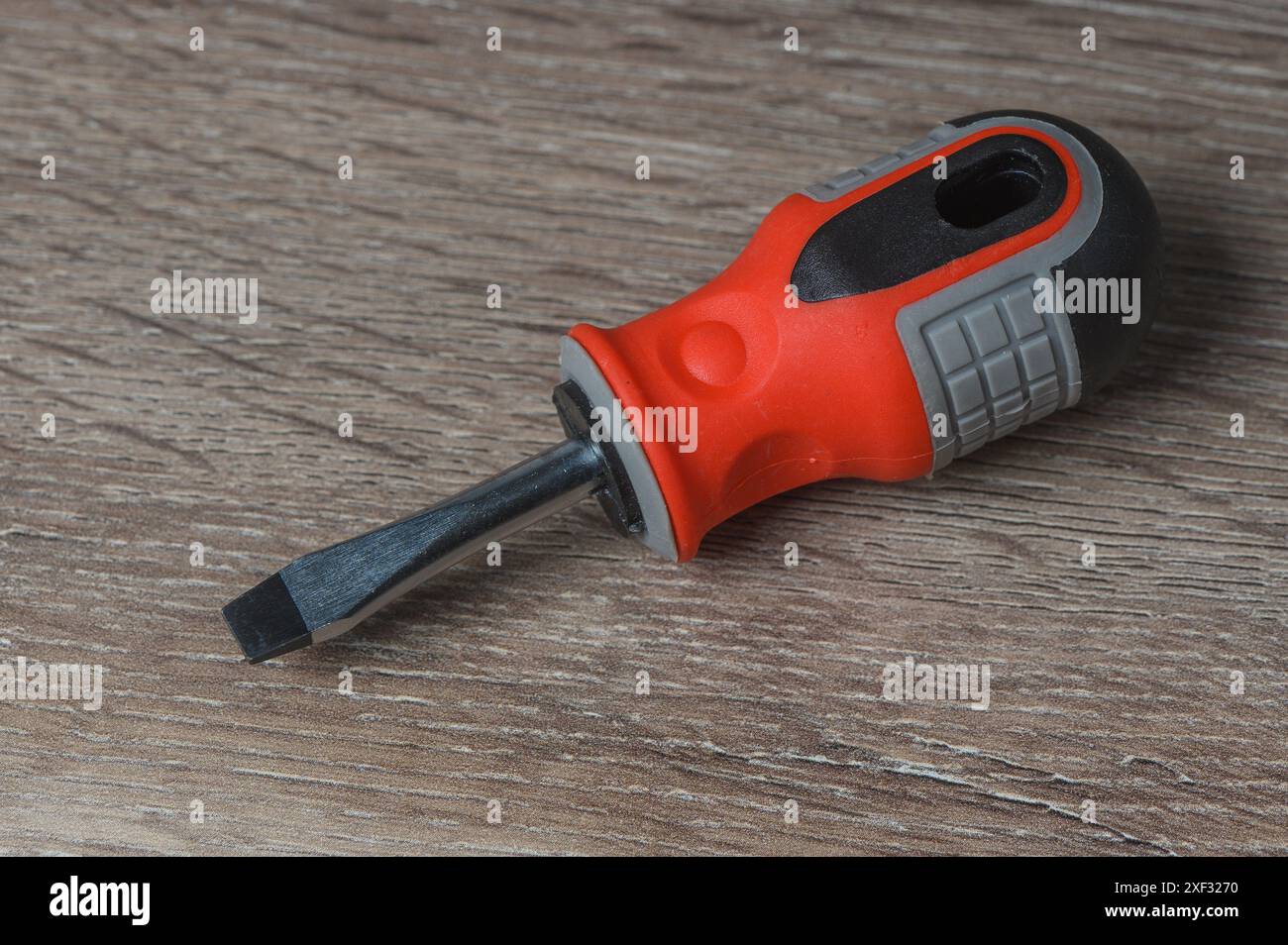 A flat head screwdriver on a wood background Stock Photo - Alamy