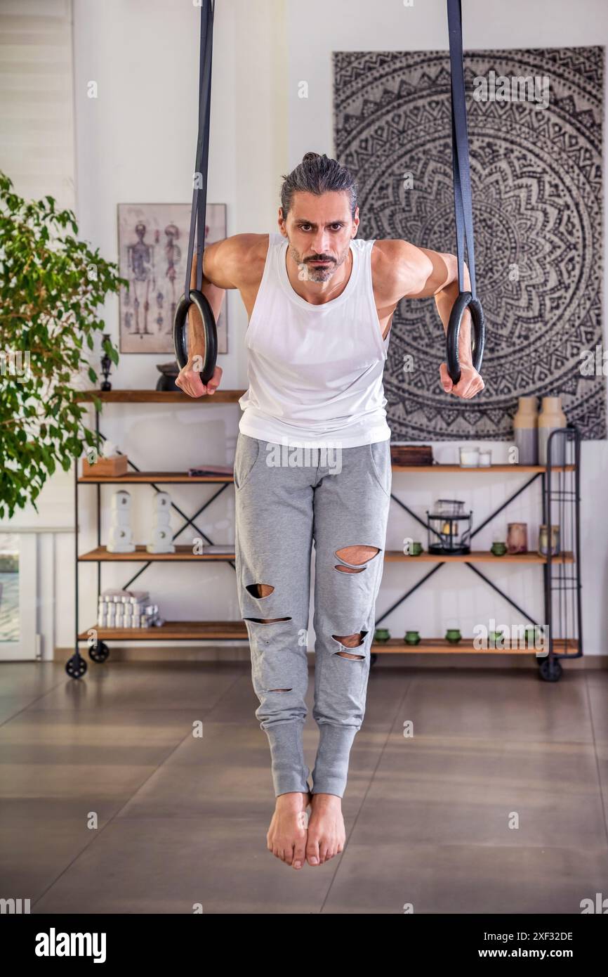 Fit man intensely performing ring dips, showcasing strength and focus ...