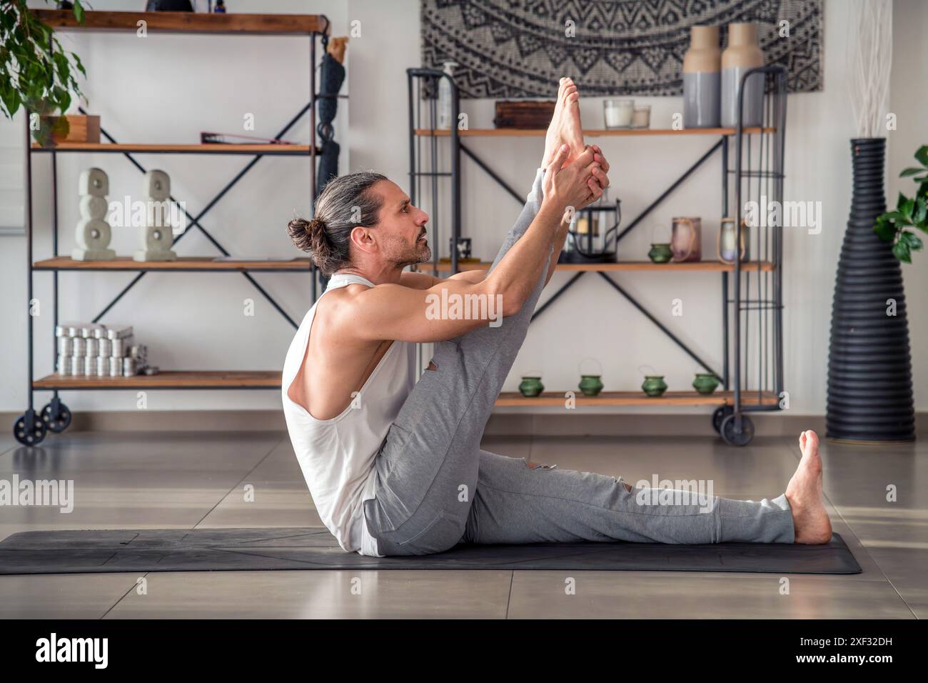Side view of strong bearded adult male looking up while sitting on mat ...
