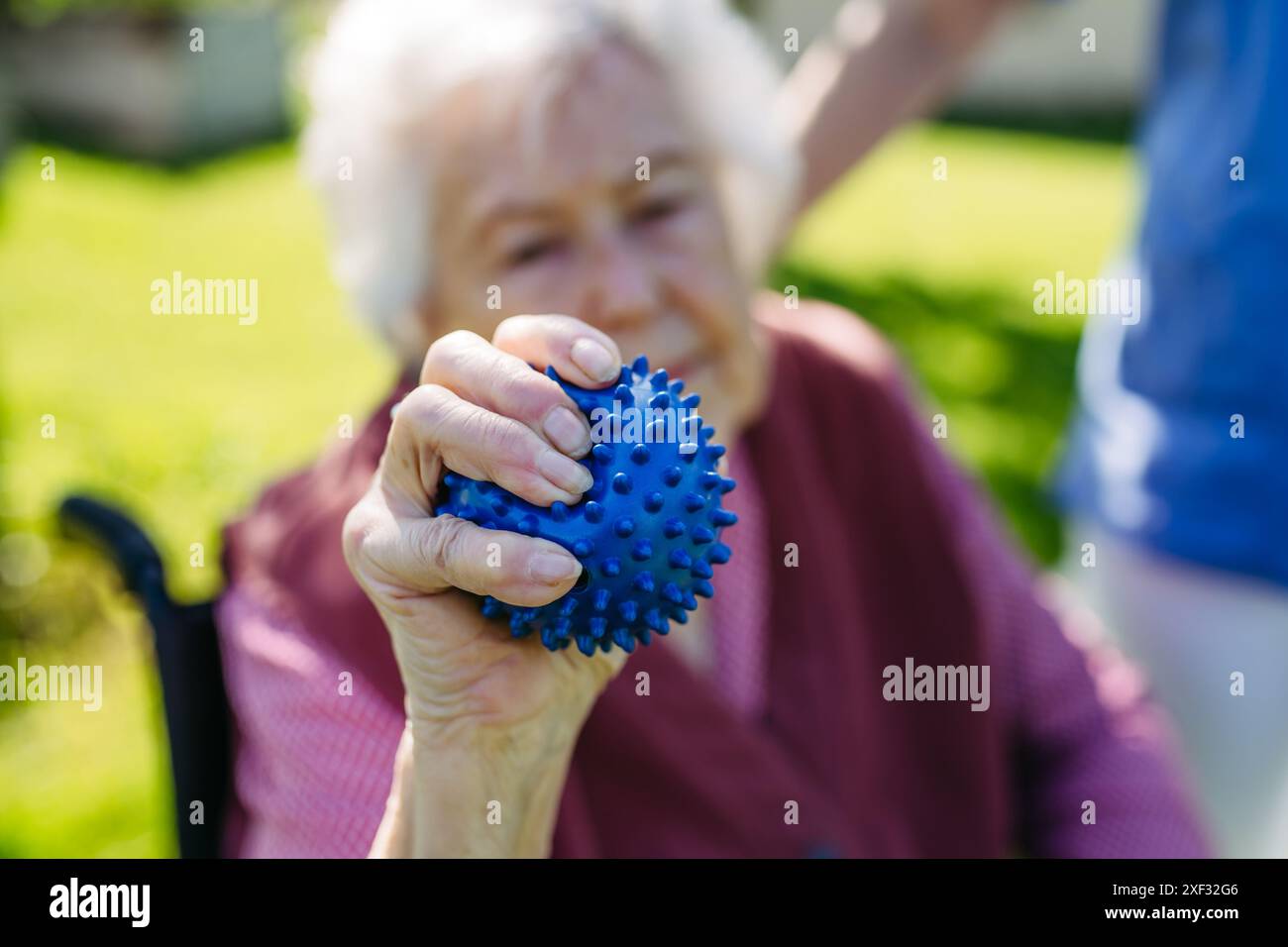 Female caregiver doing motorized exercises with senior woman in ...