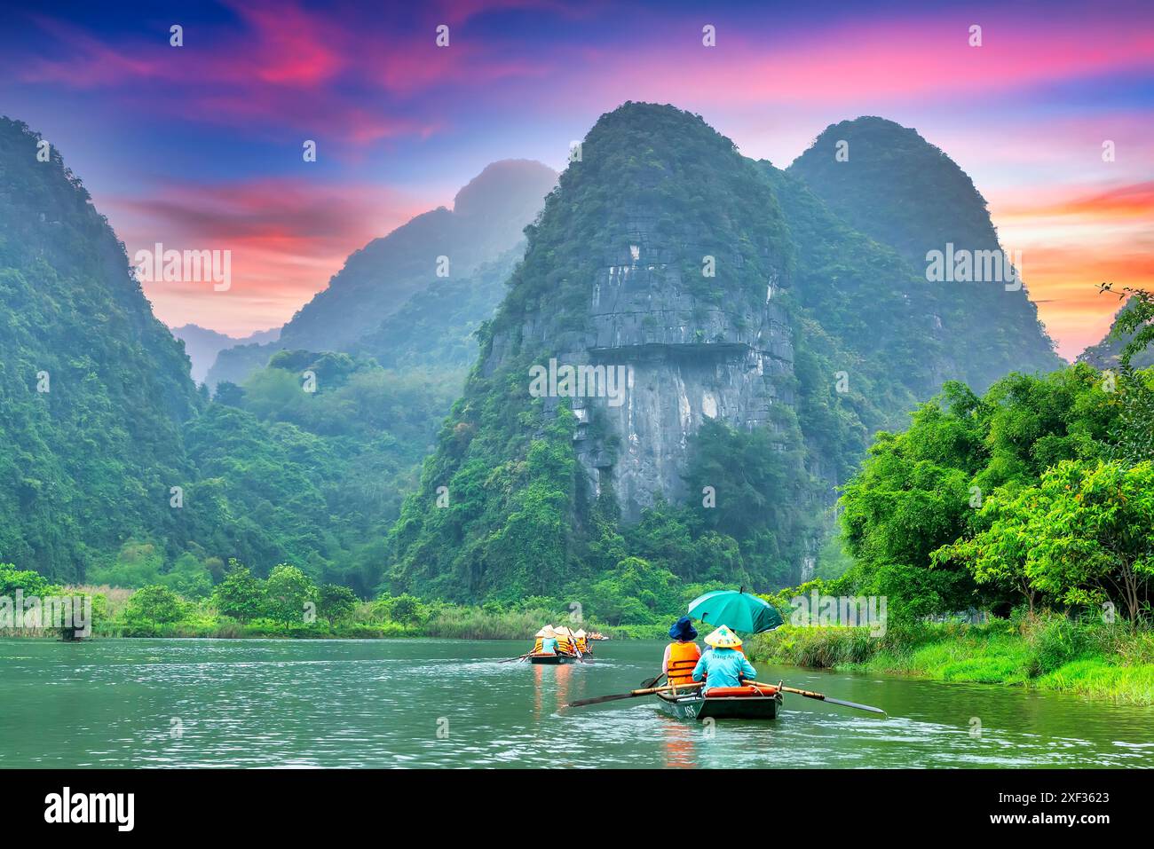 Tourists float by boat on the river of the Tam Coc National Park ...