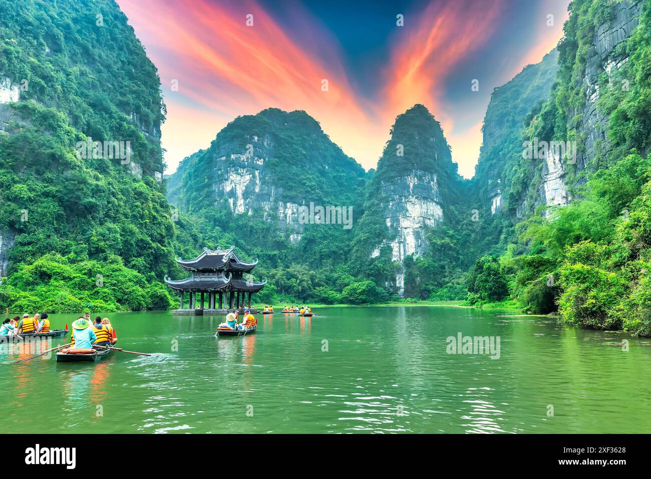 Tourists float by boat on the river of the Tam Coc National Park ...