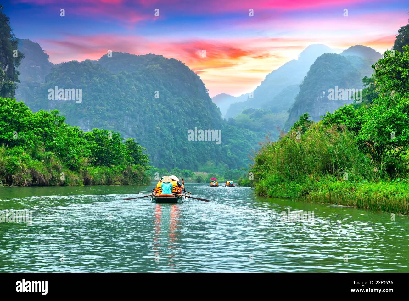 Tourists float by boat on the river of the Tam Coc National Park ...