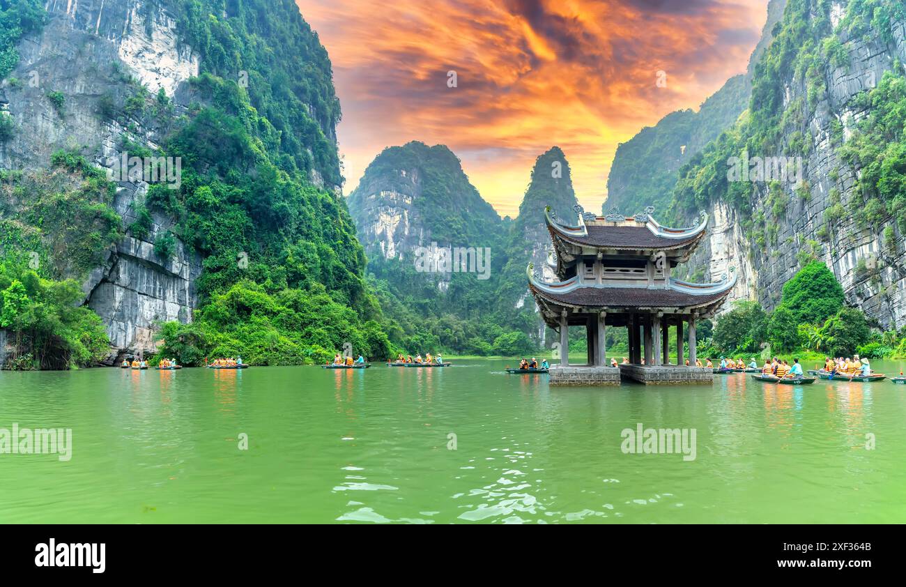 Tourists float by boat on the river of the Tam Coc National Park ...