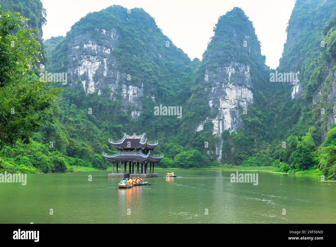 Tourists float by boat on the river of the Tam Coc National Park ...