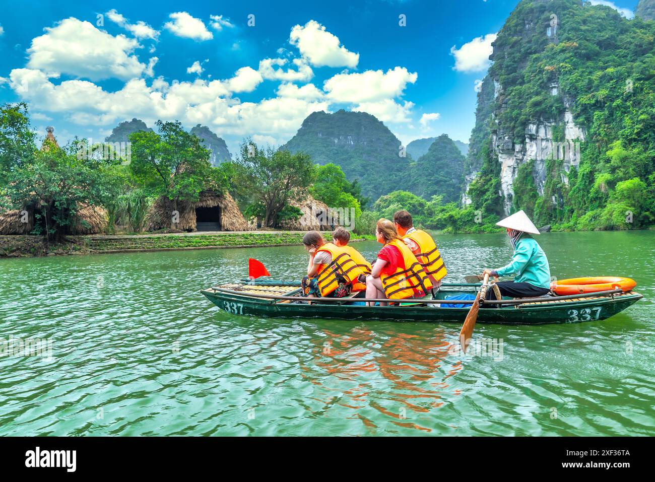 Tourists float by boat on the river of the Tam Coc National Park ...