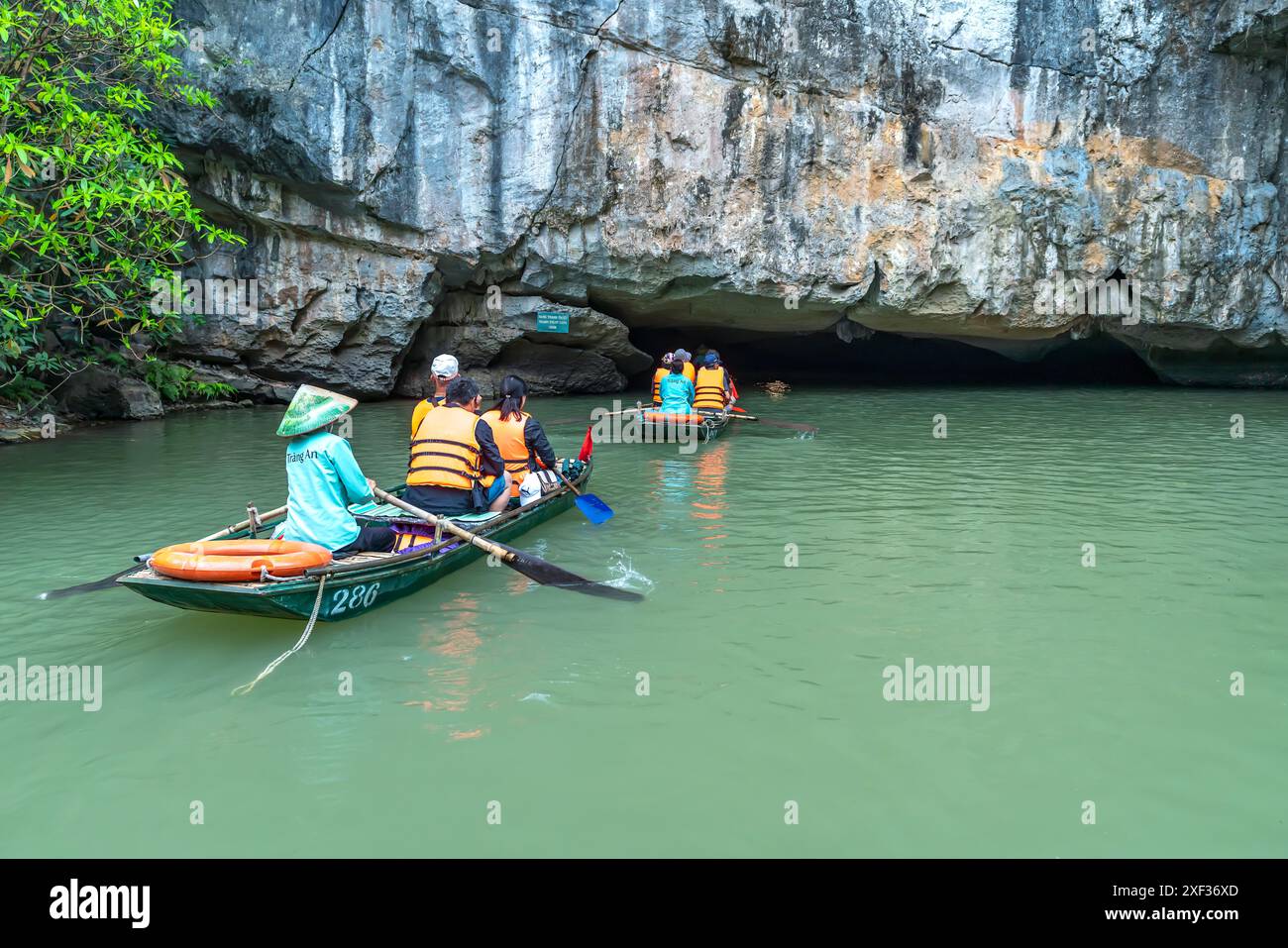 Tourists float by boat on the river of the Tam Coc National Park ...