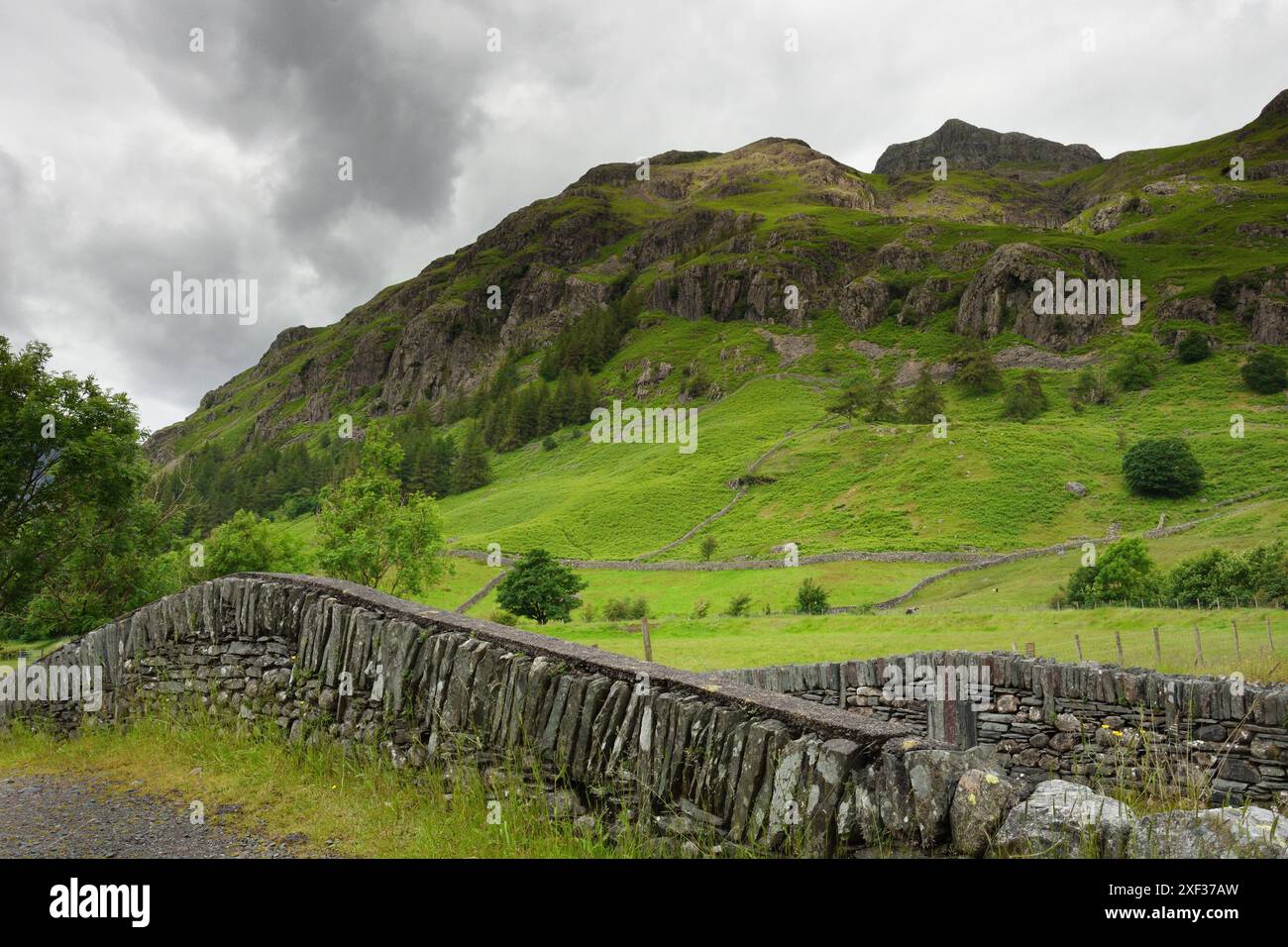 Traditional slate stone bridge with green fields and mountains in the ...