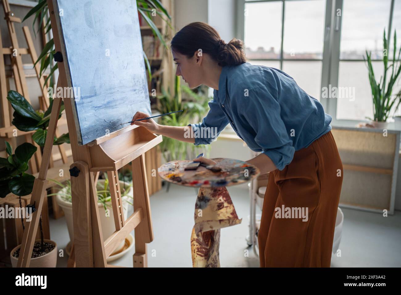 Serious female artist working on artwork masterpiece, deeply immersed ...