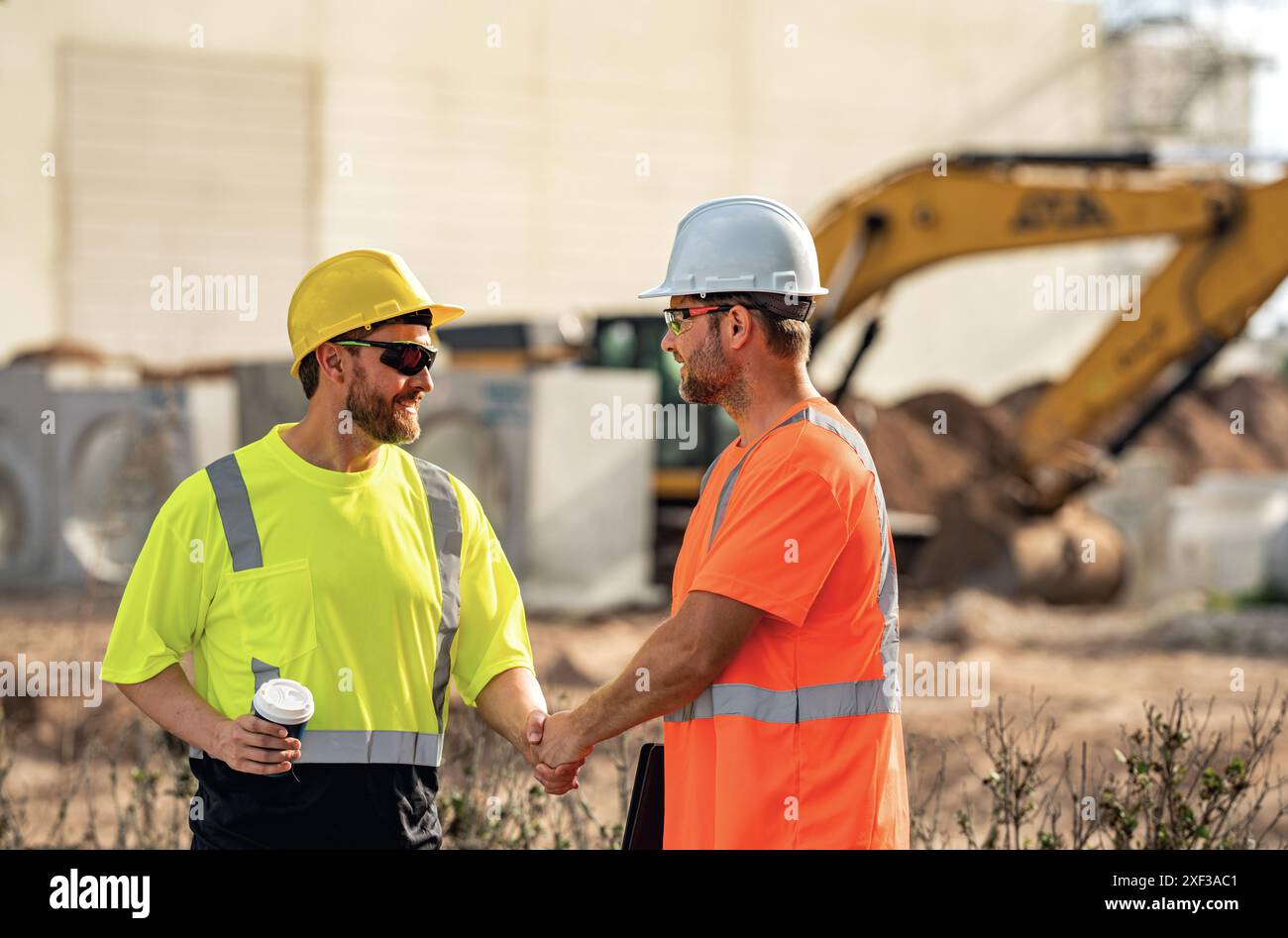 Two construction site workers in helmet work outdoors. Builders workers ...