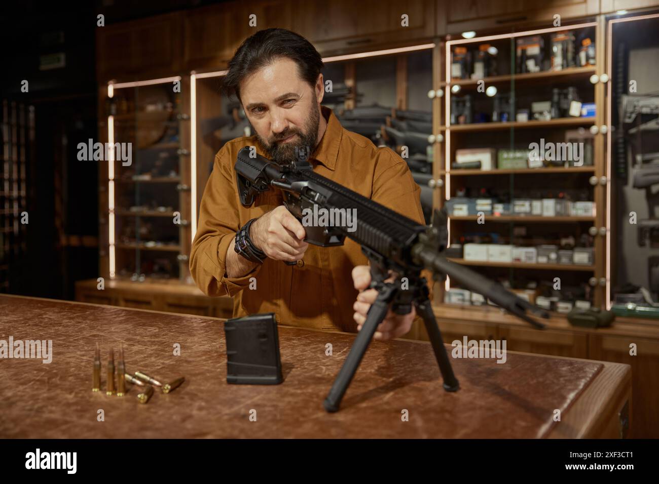 Confident male customer testing new model of automatic rifle in weapon ...