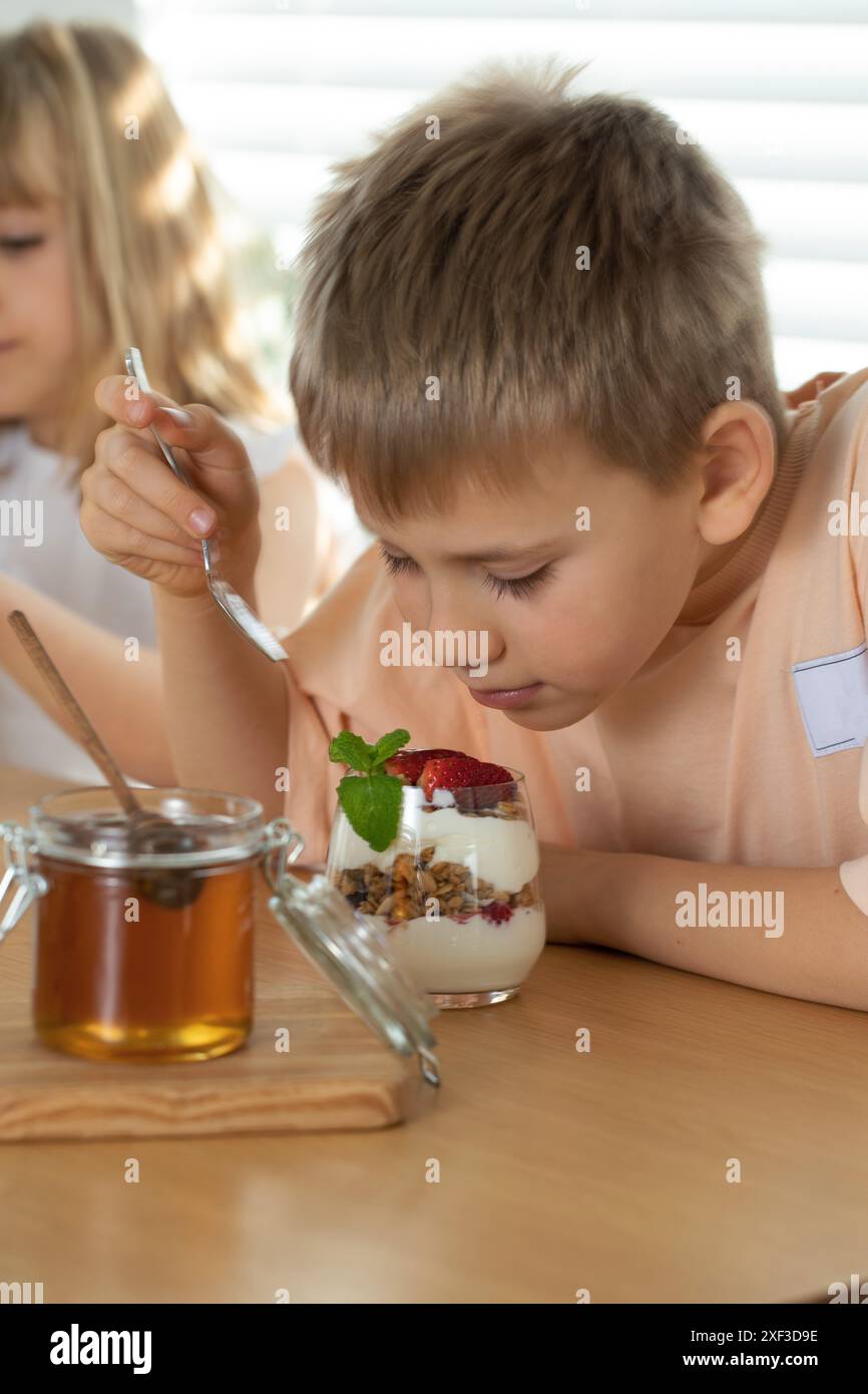 Children enjoy a healthy breakfast of granola with yogurt Stock Photo ...