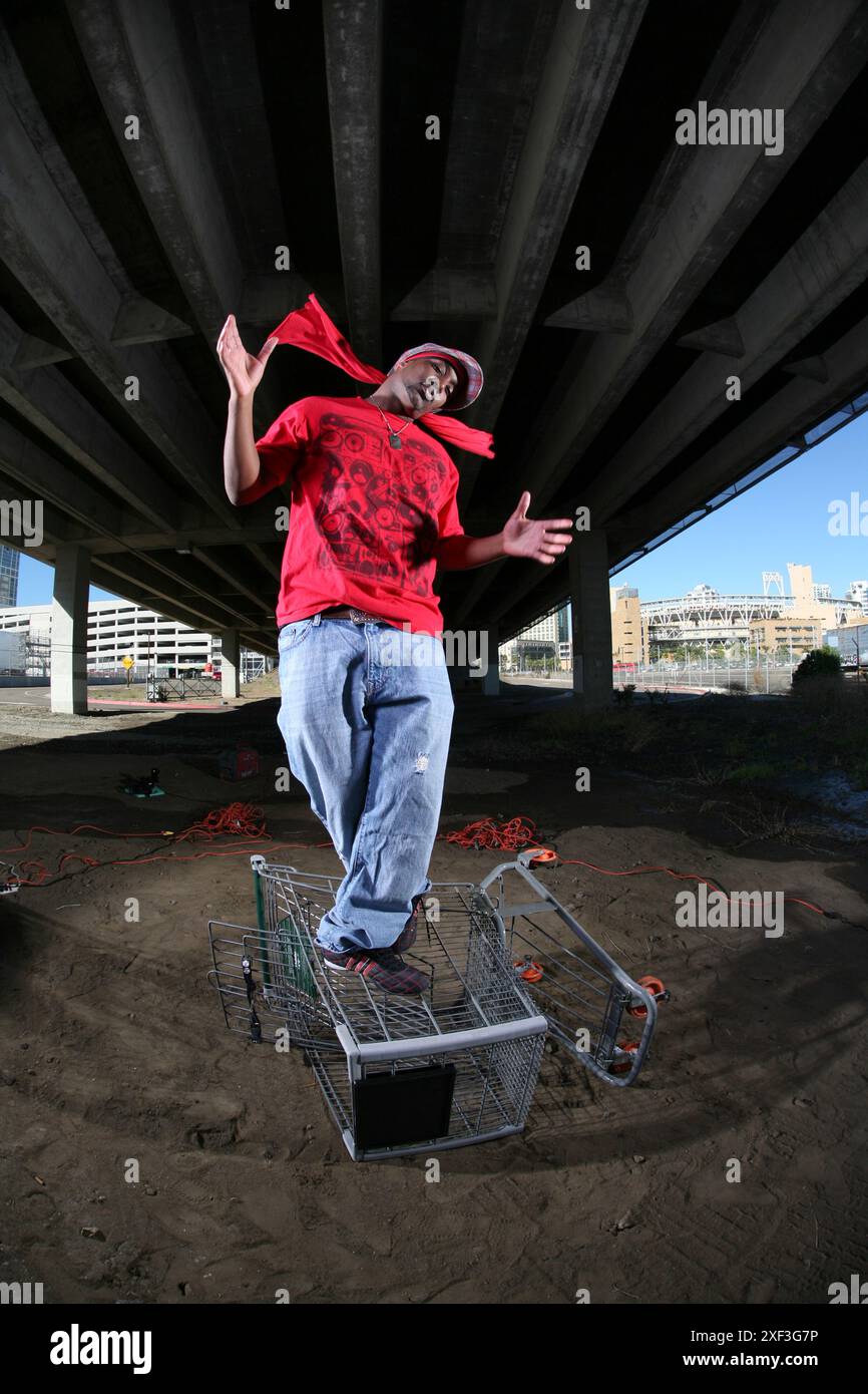 An African-American rapper and dancer stands under a bridge in an urban ...
