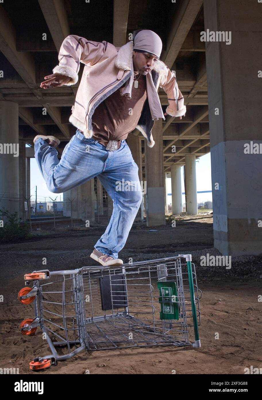 An African-American rapper and dancer stands under a bridge in an urban ...