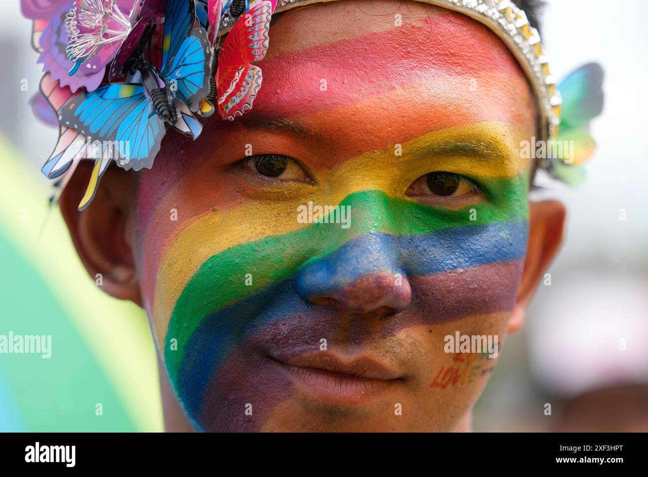 A participant with a rainbow painted on his face takes part in the ...