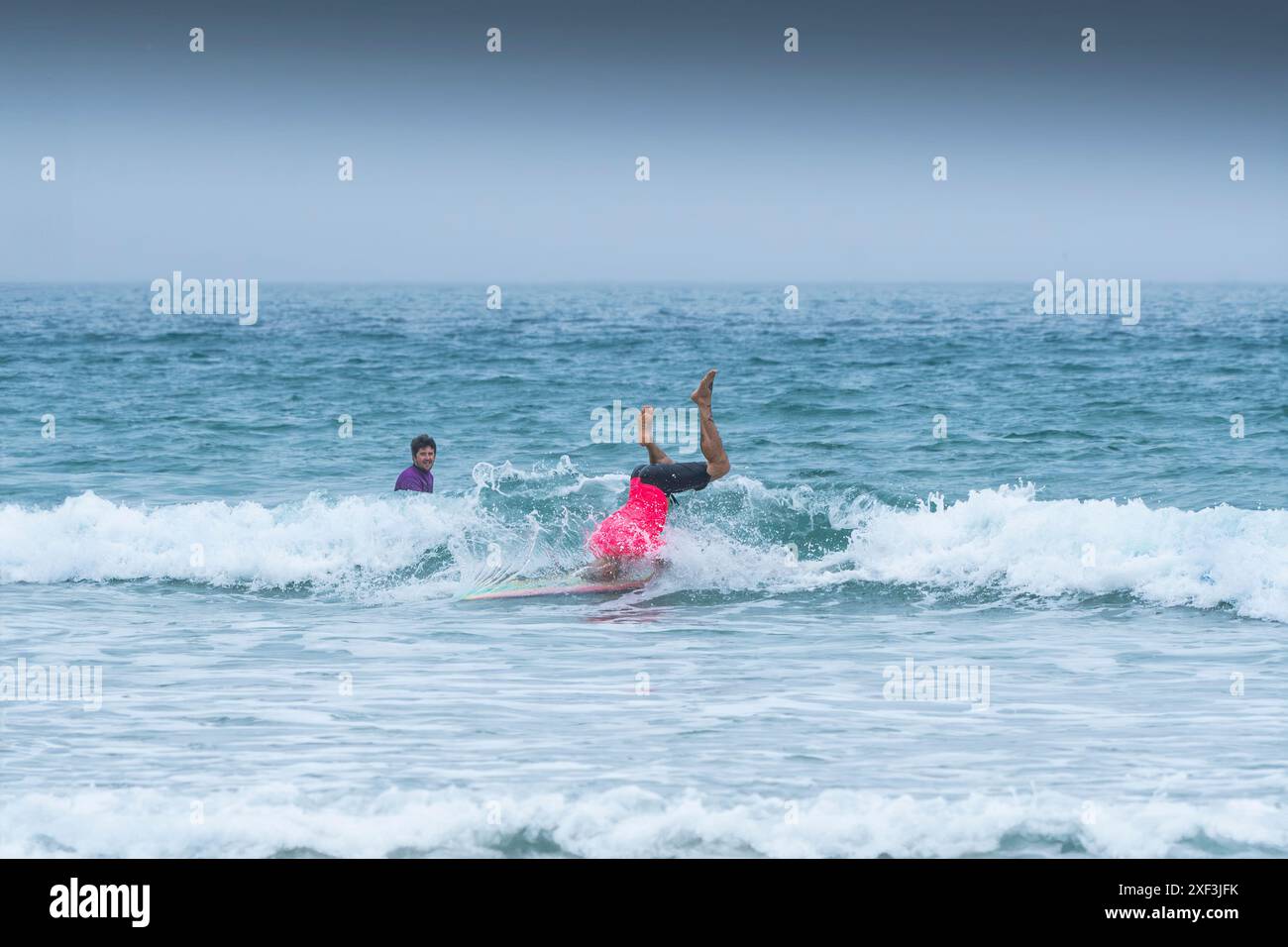 An enthusiastic surfer attempting a handstand on his surfboard in the ...