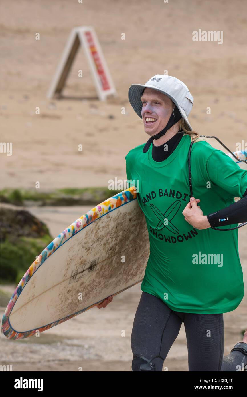A happy laughing surfer carrying his surfboard running to the sea to ...