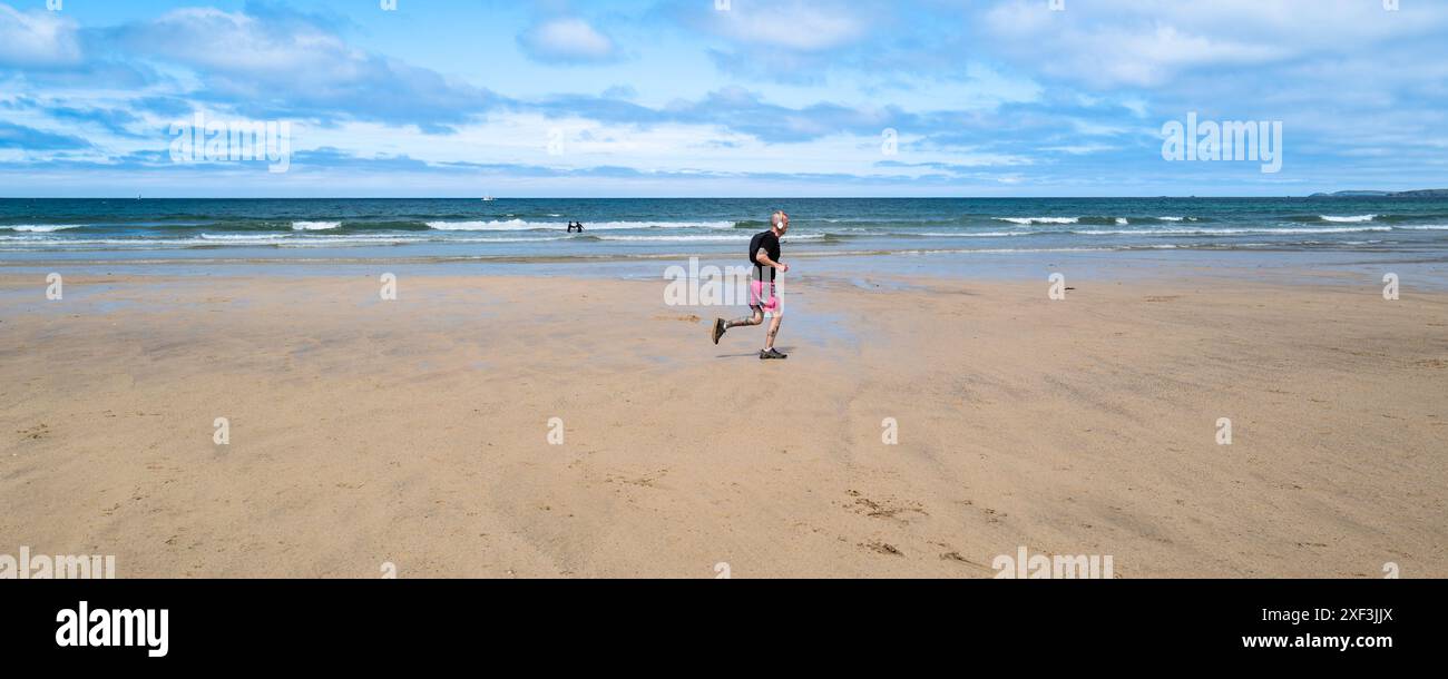 A panoramic image of a lone man running across Great Gt Western beach ...