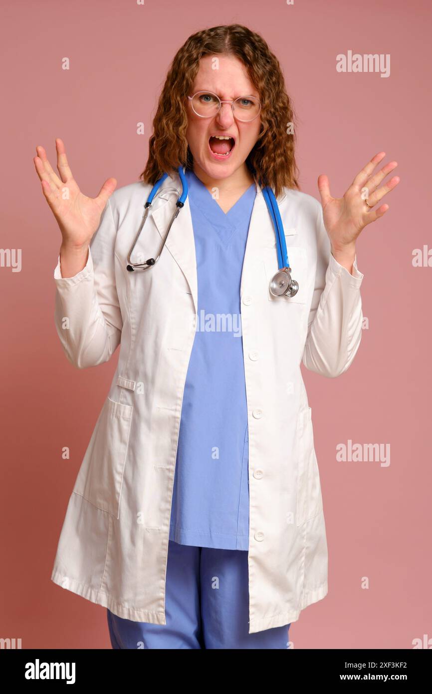 Furiously screaming female doctor, studio pink background. Nurse in ...