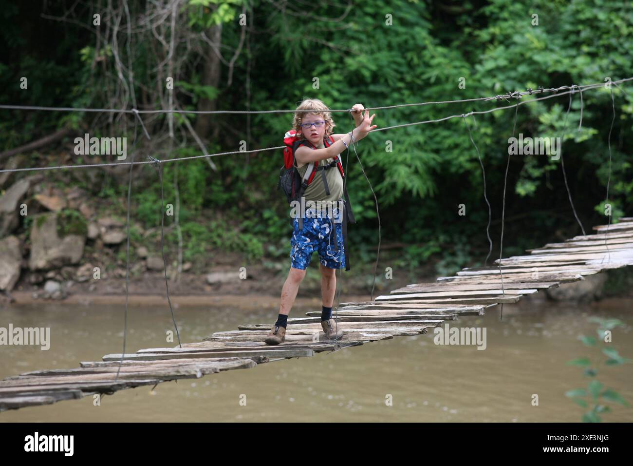 Thailand, Chiang Mai province; Boy walk on a wooden suspension bridge ...