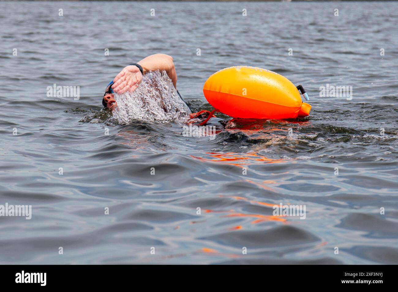 Close up of a women swimming in open water wearing an orange safety ...