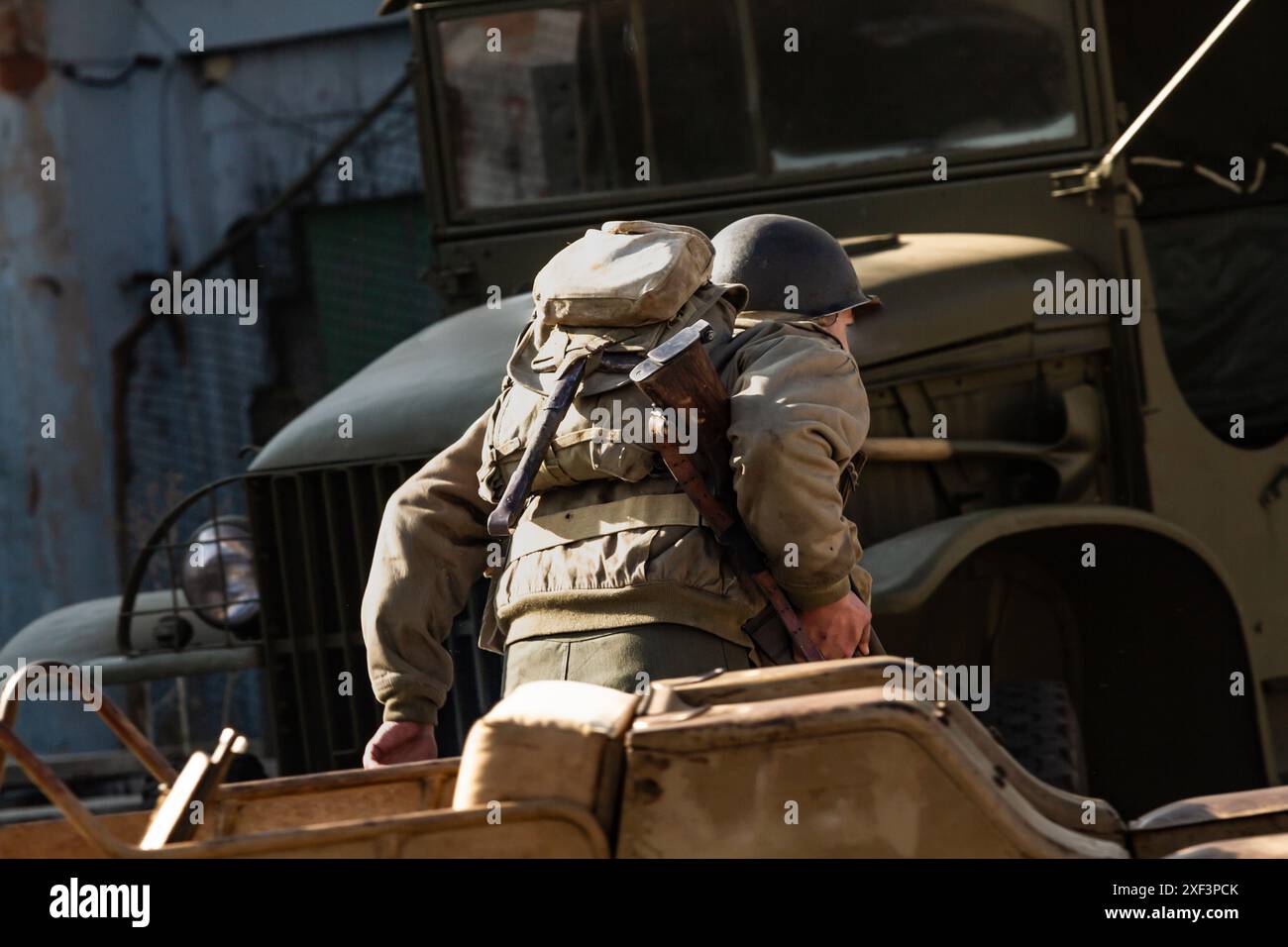 A World War II infantry division soldier runs between vehicles during ...