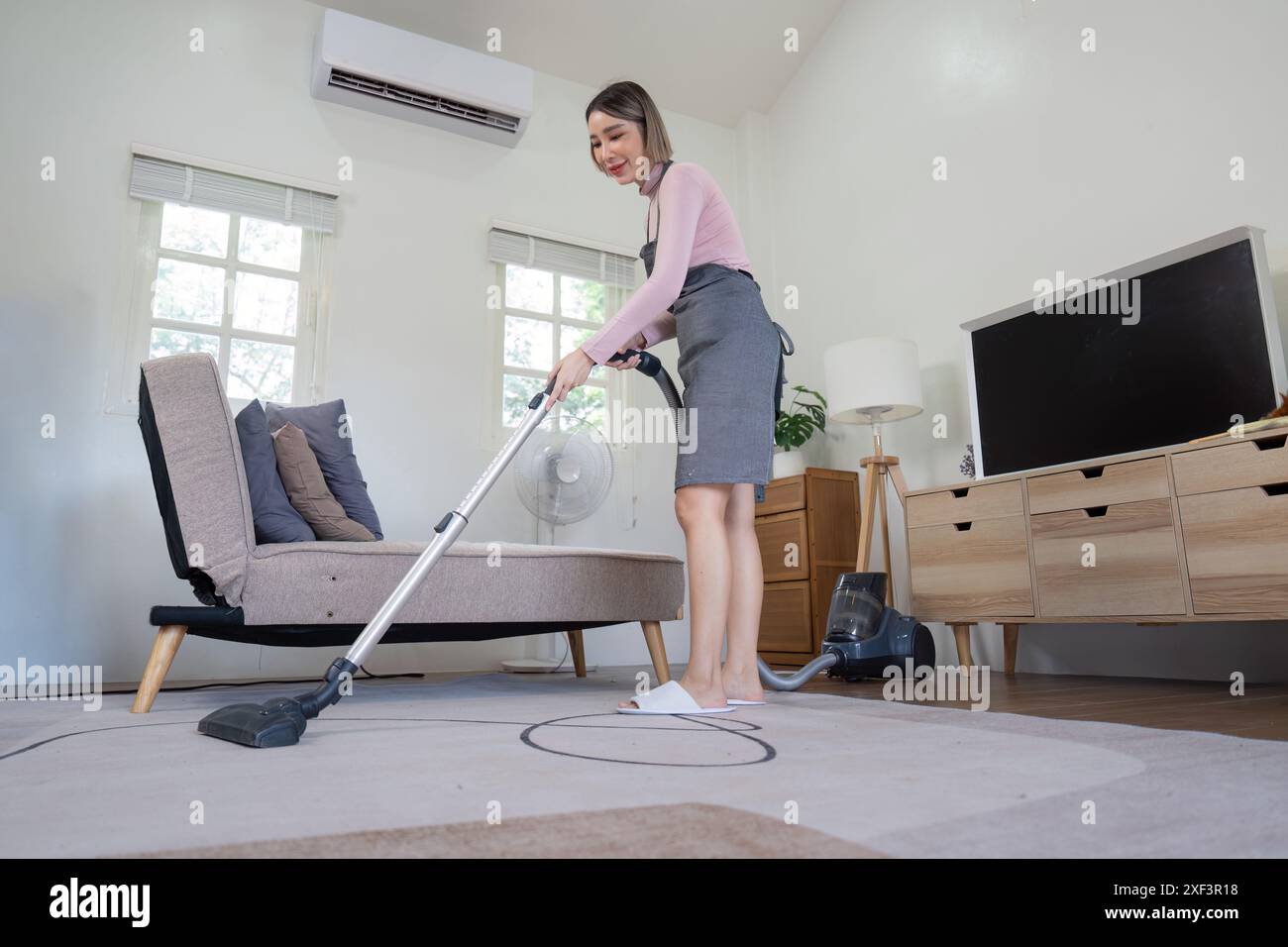 Housekeeper Cleaning Modern Living Room with Vacuum Cleaner in Bright ...