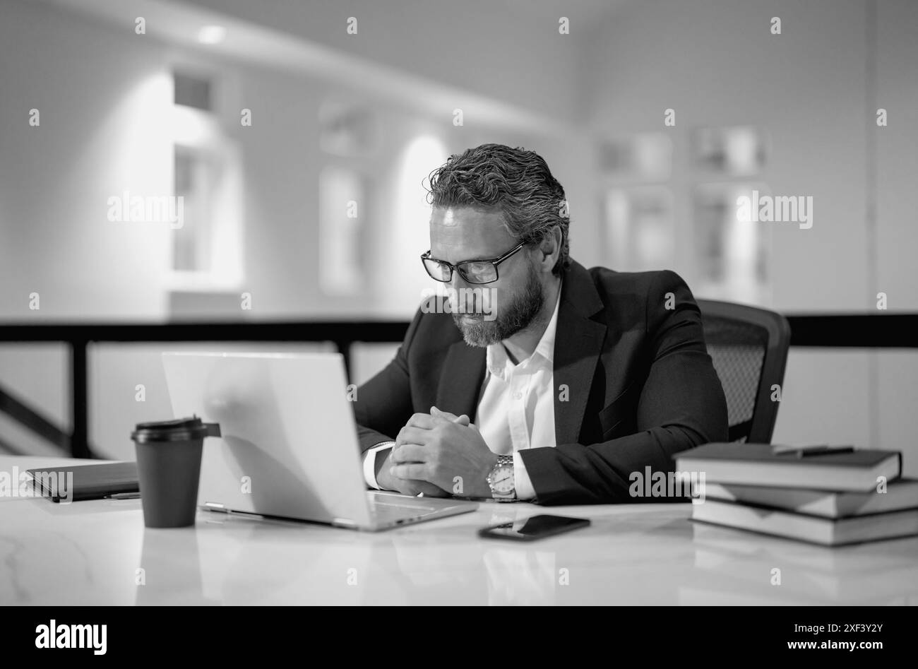Office workplace. Serious business man working with laptop at desk in office. Businessman typing ...