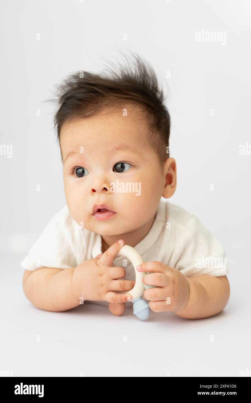 The baby boy is learning to crawl and playing with gum, white clothes ...