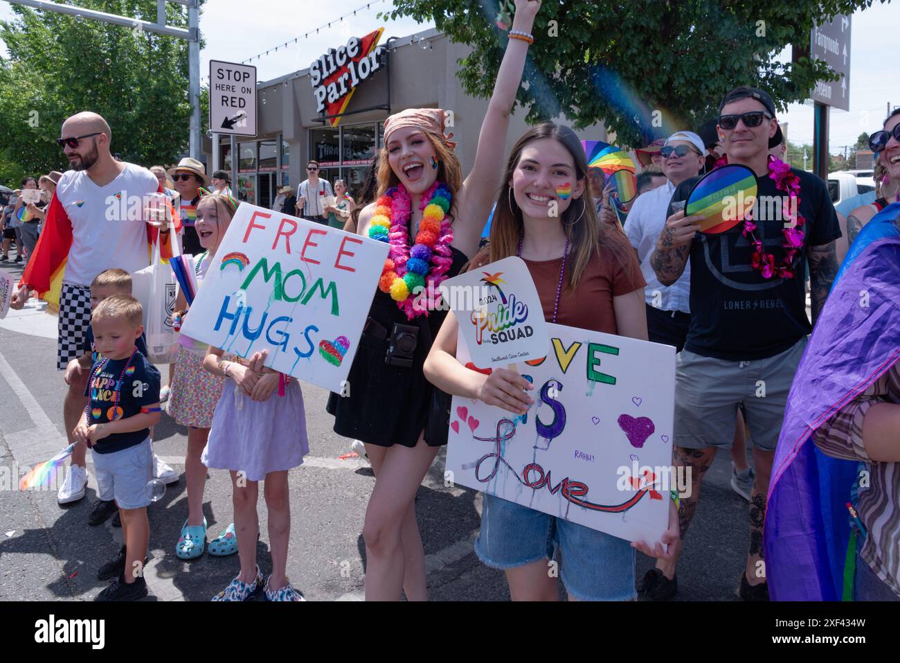 Spectators hold signs, one says Free Mom Hugs, at the Gay Pride Parade ...