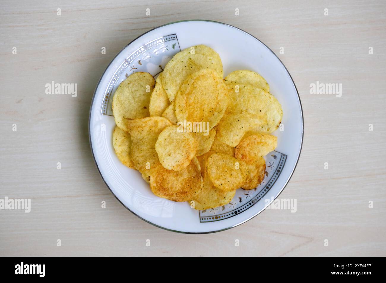 Crispy potato chips on a white plate on wooden background. Crunchy ...