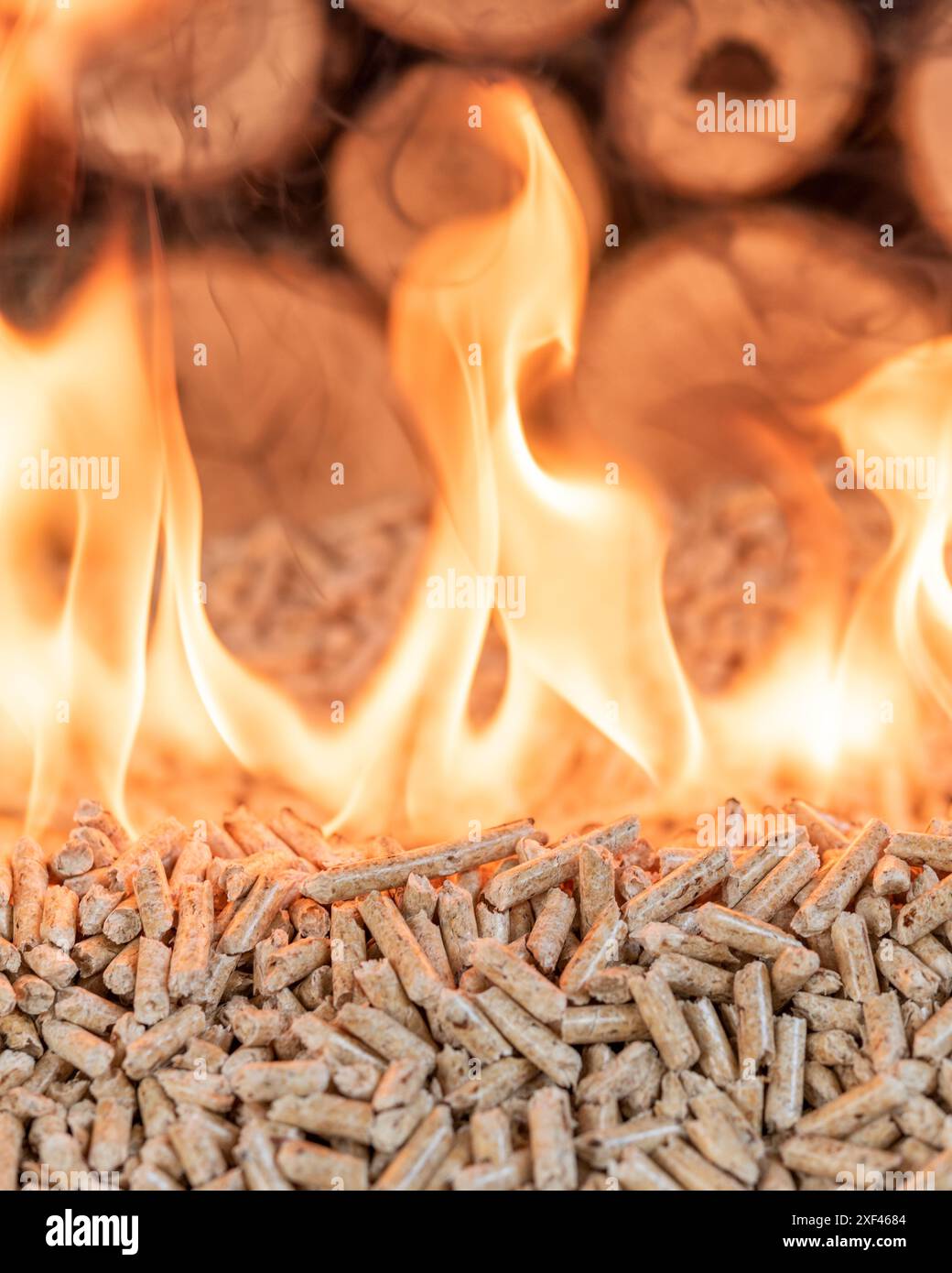 A pile of wood pellets on fire. Behind in defocus there is a wall of ...