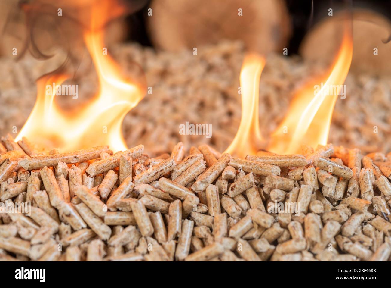 A pile of wood pellets on fire. Behind in defocus there is a wall of ...