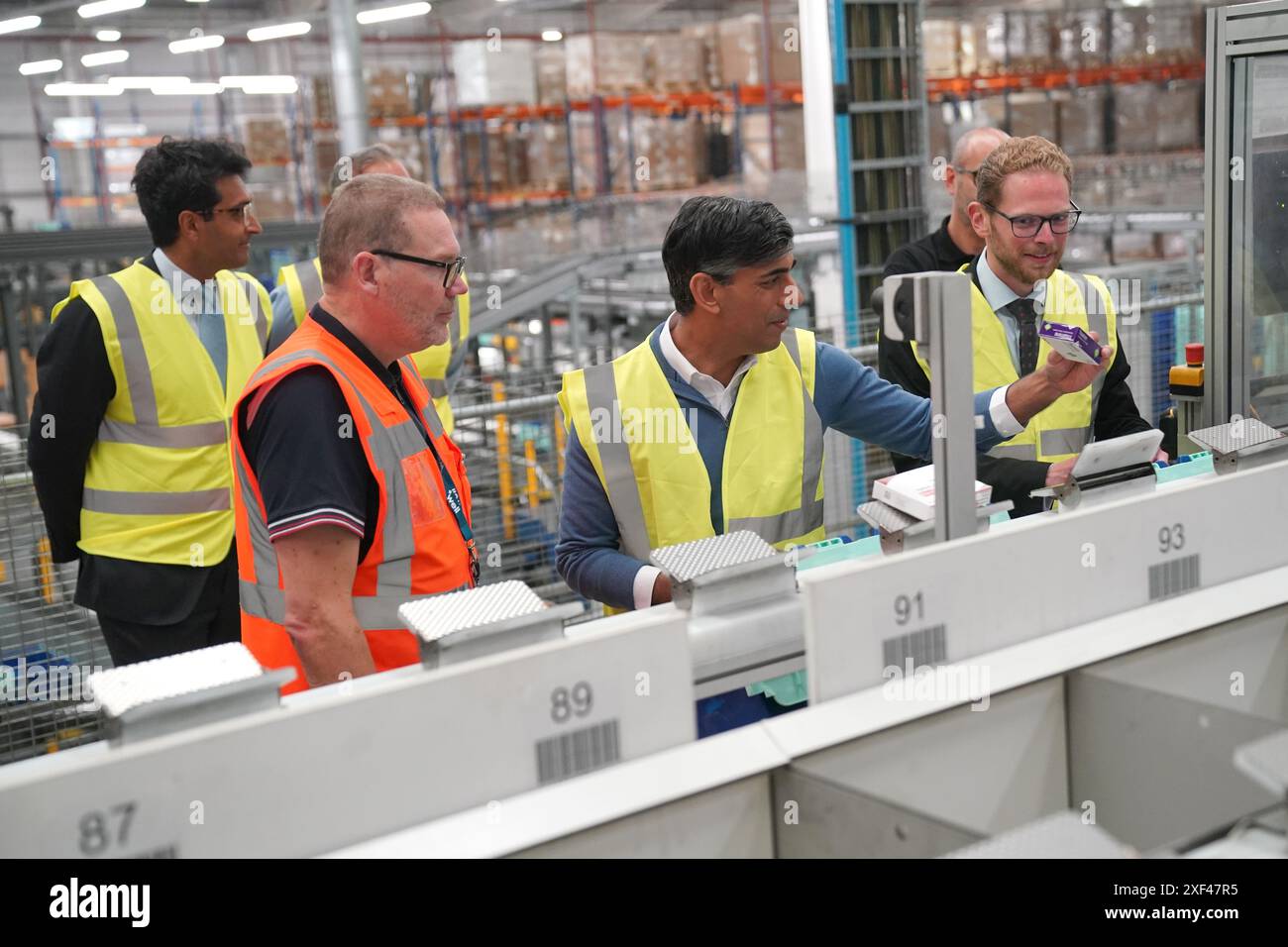 Prime Minister Rishi Sunak placing boxes on a conveyer belt during a ...