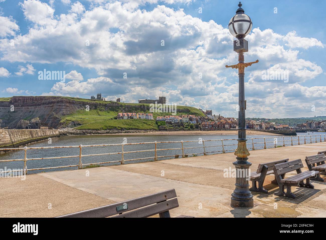 A view of a far hillside from a pier with a streetlight and benches ...