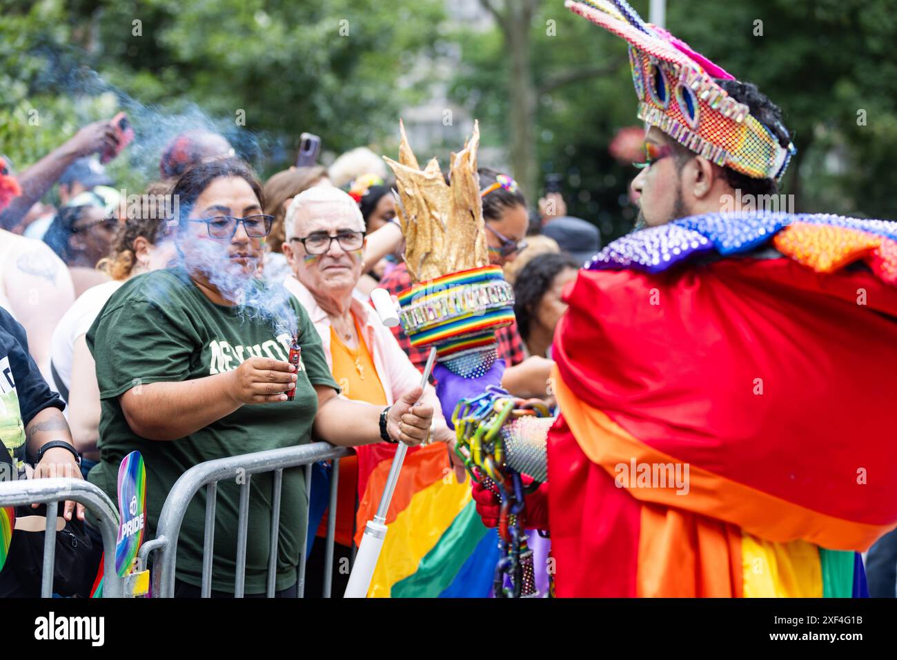 A crowd member helps a participant in the NYC Pride March light their ...