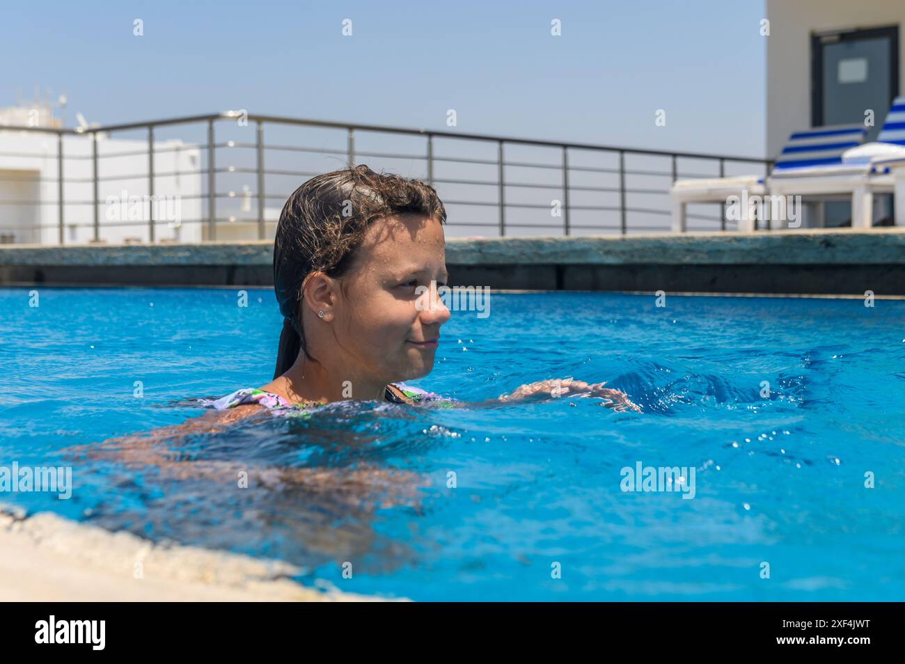 Oriental appearance smiling female kid is posing in calm blue water ...