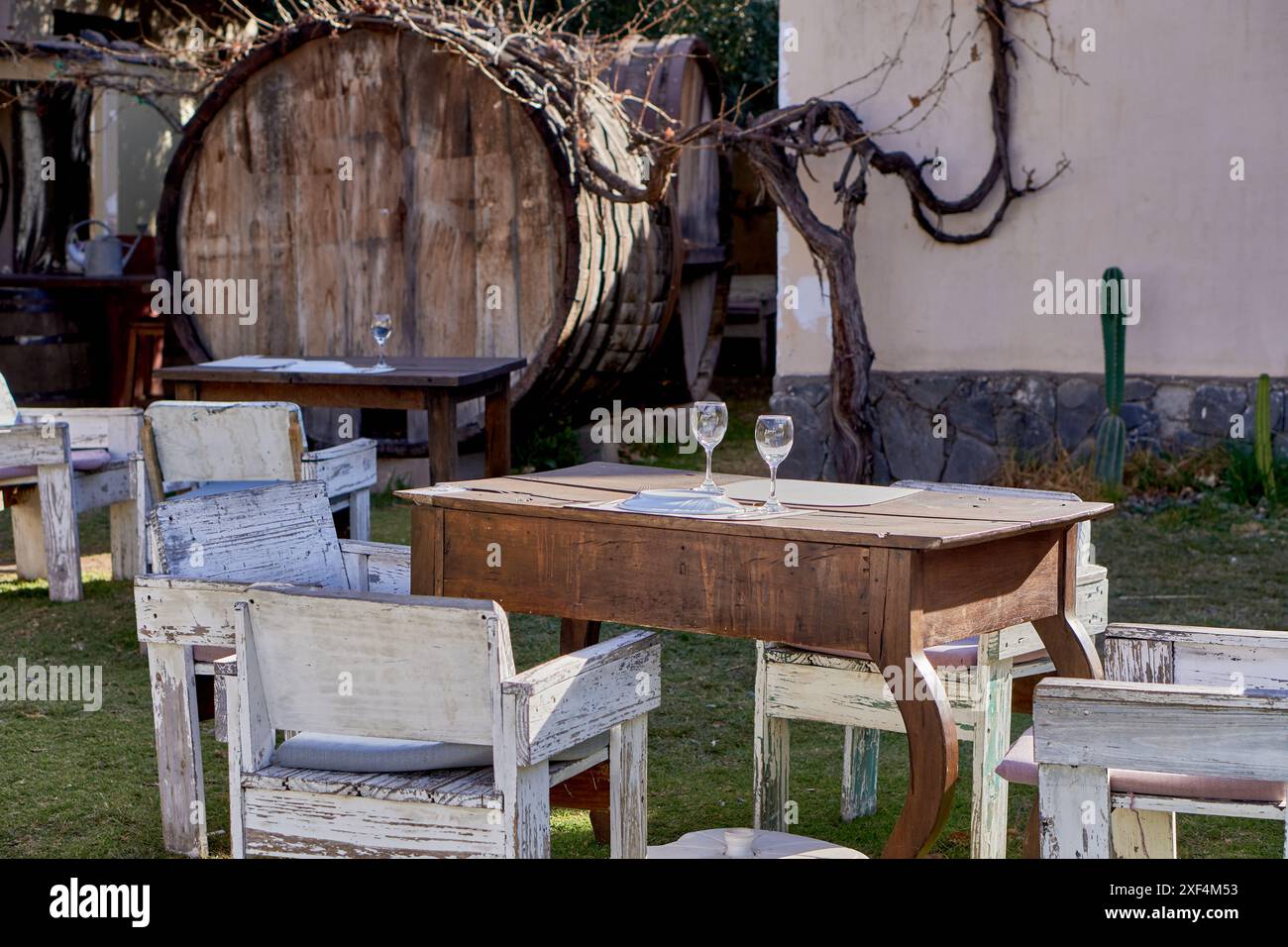 Rustic wooden table with chairs with 2 empty glasses in the backyard of ...